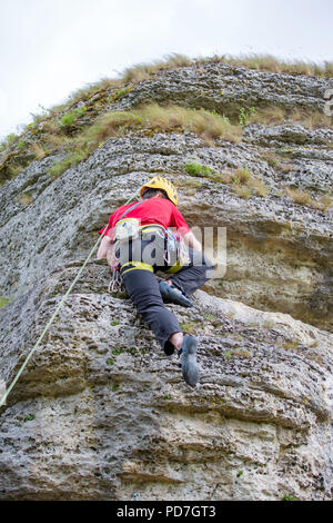 Young man climbs up an outdoors rock wall Stock Photo - Alamy