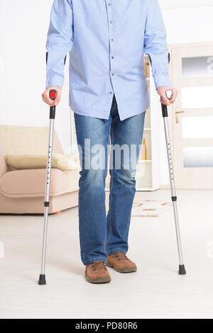 Injured man with crutches recovering at home Stock Photo - Alamy