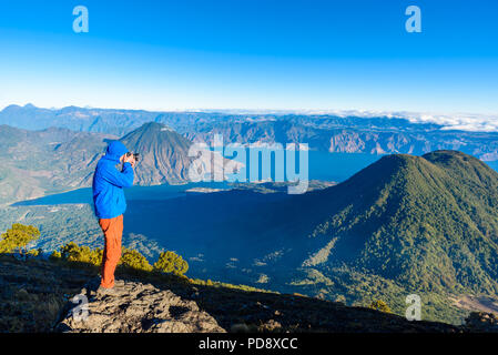 Hiker with panorama view of Lake Atitlan and volcano San Pedro and ...