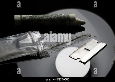 Party drugs cocaine, baggie, razor blade and rolled up money on a black ...