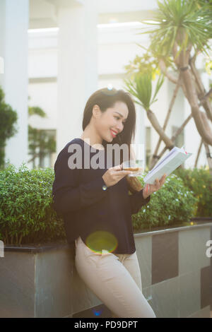 Relaxing with her favorite book. A young woman lying on the couch with ...