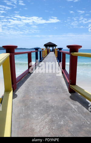 Colorful concrete and wooden jetty jutting out over a white sandy beach ...