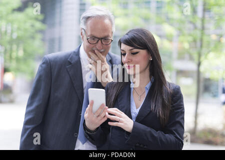 Smiling businesswoman and her boss using her cell phone Stock Photo - Alamy
