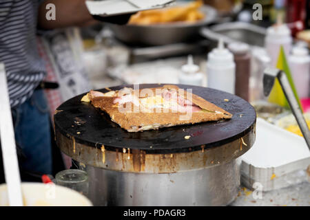 Preparing crepe, galette with ham, cheese and egg on black plate. Cook ...