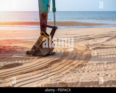 excavator that is working on the beach to smooth the sand before the ...