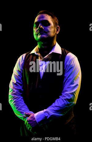 Sinister man with Halloween skeleton makeup making faces, looking at ...