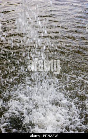 transparent falling water vertical flows against a blue sky and green ...