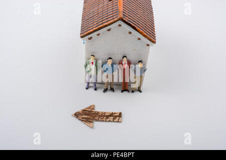 Tiny figurine of men and an arrow in front of a model house Stock Photo ...