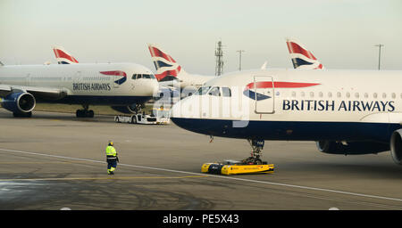 Airport worker operating a remote controlled tug at London Heathrow ...