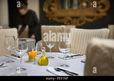 Restaurant table setting with staff member in soft focus background ...