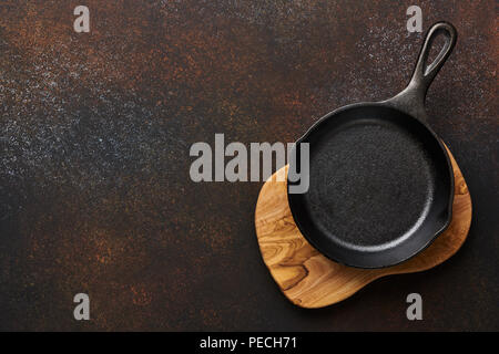 Brown iron empty pan with kitchen utensils on a dark concrete ...