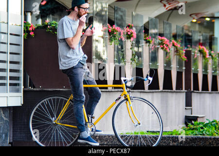 cigarette in the hand of a smoking cyclist who rides a bike on the ...