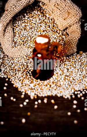Close up of pearl millet oil with raw pearl millet on a wooden surface ...