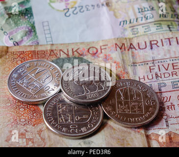 Mauritius Rupee (MUR) notes and coins with red background - close up ...
