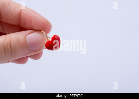 Red color heart shape earring in hand on white Stock Photo - Alamy