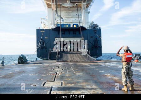 A sailor directs a seven-ton truck onto landing craft utility 1650 ...