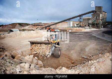 Excavating and picking up mined aggregate from the quarry floor, in a ...
