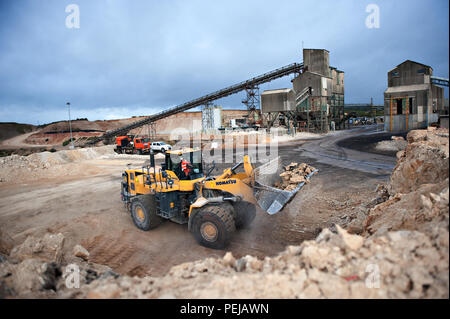 Excavating and picking up mined aggregate from the quarry floor, in a ...