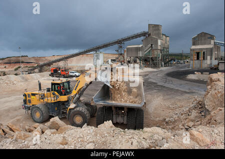 Excavating and picking up mined aggregate from the quarry floor, in a ...