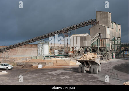 Excavating and picking up mined aggregate from the quarry floor, in a ...
