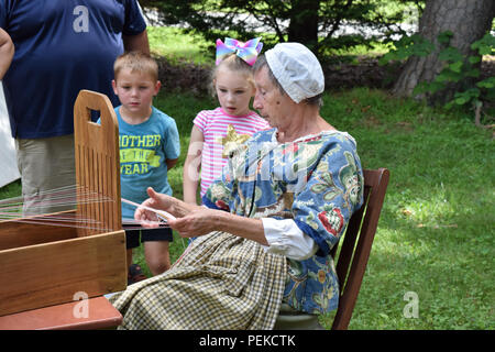 A woman giving a demonstration of using a Hand Loom from colonial times ...