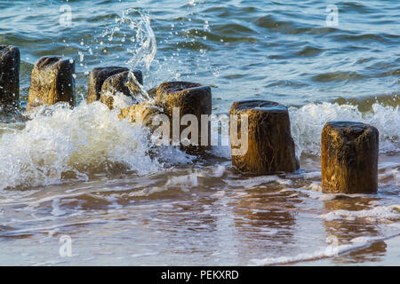 Water splashing against wooden pier submerged in deep green blue water ...
