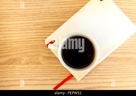 Coffee cup over a paper notebook on a table Stock Photo - Alamy