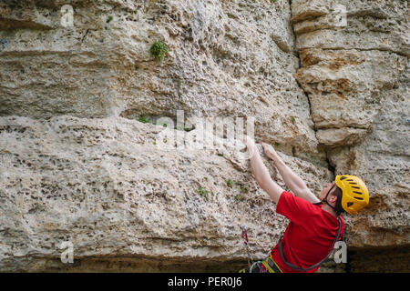 Photo of man in helmet clambering over rock up Stock Photo - Alamy