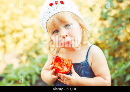 independent kid eating a tomato, standing in nature Stock Photo - Alamy
