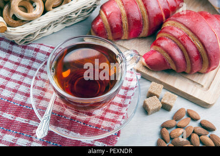 two croissants with fruit glaze and another baking and a cup of tea top ...