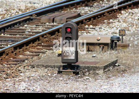 Railway trackside red and green traffic signal lights below signal sign ...