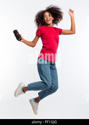 Charming African-American teenager listening to music near light wall ...