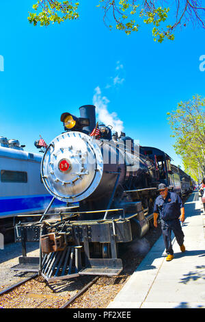 Red, blue and silver trains at a station with many railroads and a ...