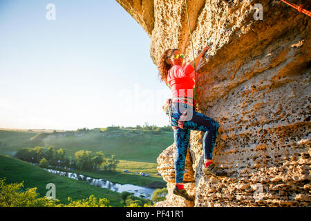 Picture of curly-haired female tourist clambering over rock Stock Photo ...