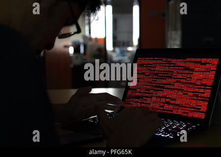 Computer Hacker silhouette typing on computer in a dark room. Working on binary code technology ...