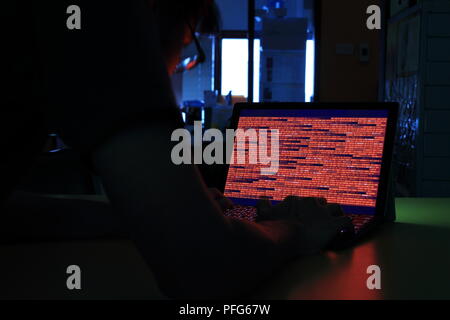 Computer Hacker silhouette typing on computer in a dark room. Working on binary code technology ...