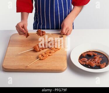 Close-up of marinated meat skewers grilling over hot charcoal, with ...