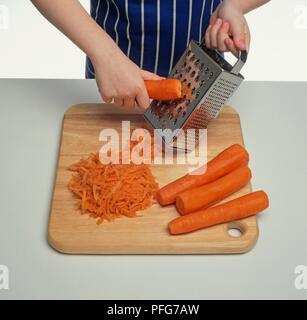 A close-up of a hand using a grater to grind fresh parmesan cheese ...