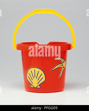 Horizontal view of a red plastic bucket and spade lying in the sand on ...