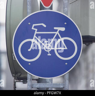 A blue and white sign with a bicycle image against a cloudy sky ...