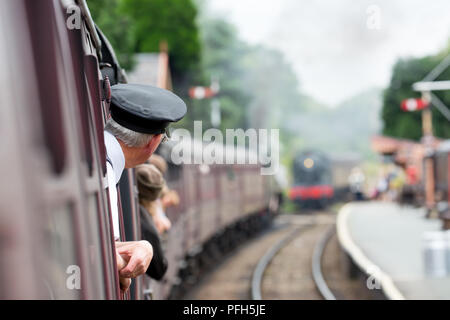 Steam train conductor leaning out of passenger car window Stock Photo ...