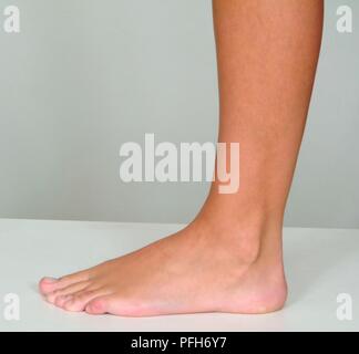 Side view close up of a young woman wearing red shoes sat outdoors ...