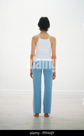 Woman standing upright, hands beside body, feet slightly apart, facing ...