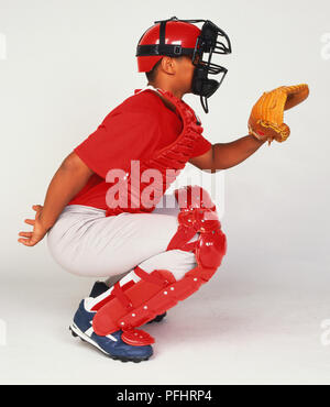 Side view of boy crouching on grassy field during sunny day Stock Photo ...