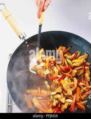 A hand is holding a yellow bell pepper above the garden while green ...