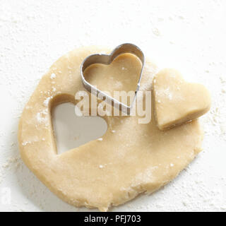 White flour heart shape on rustic wooden table with baking ingredients ...