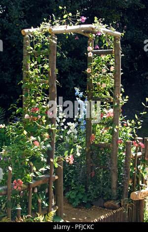 UK. A garden arch with roses and honeysuckle and patio beyond Stock ...