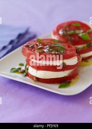 Tomato and mozzarella salad with basil on a white plate Tomato and ...