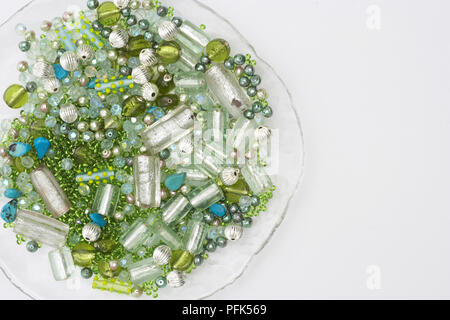 Green beads on plate on green background Stock Photo - Alamy