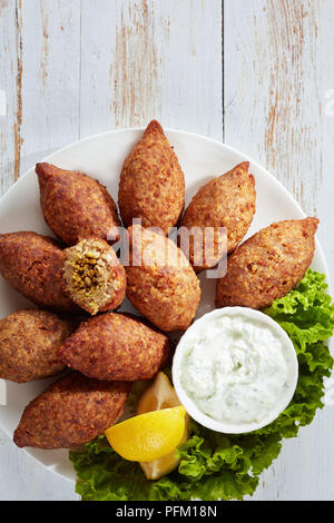 delicious fried kibbeh with yogurt sauce in a bowl served on a clay ...